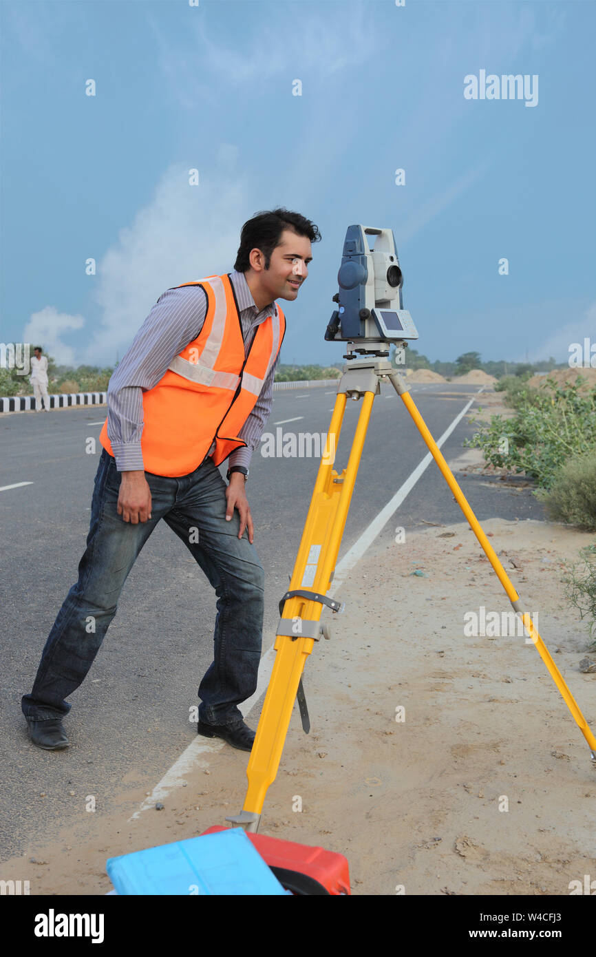 Surveyor using theodolite on tripod Stock Photo - Alamy