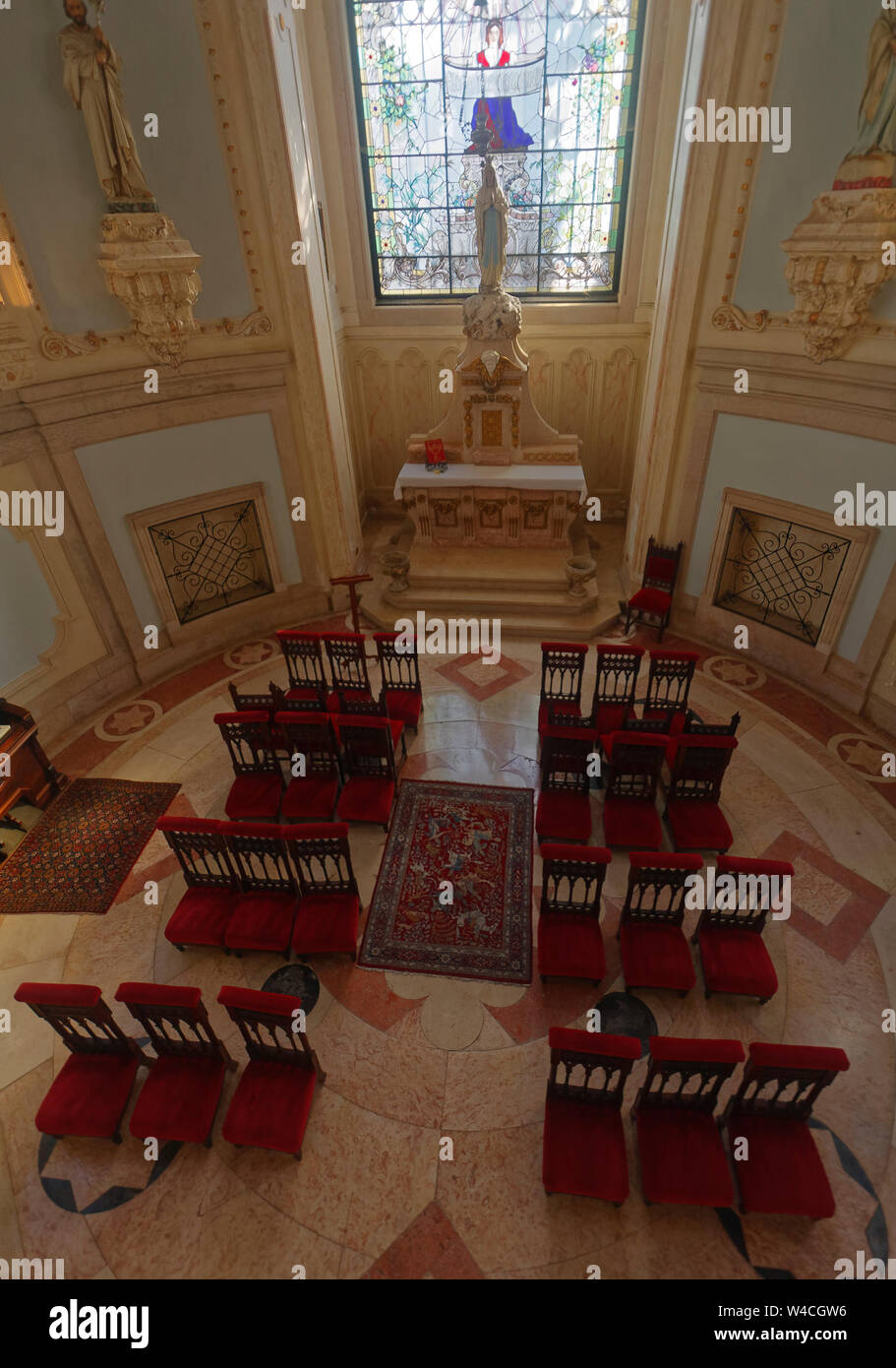 small chapel, stone altar, red kneelers, prie dieus, stained glass ...