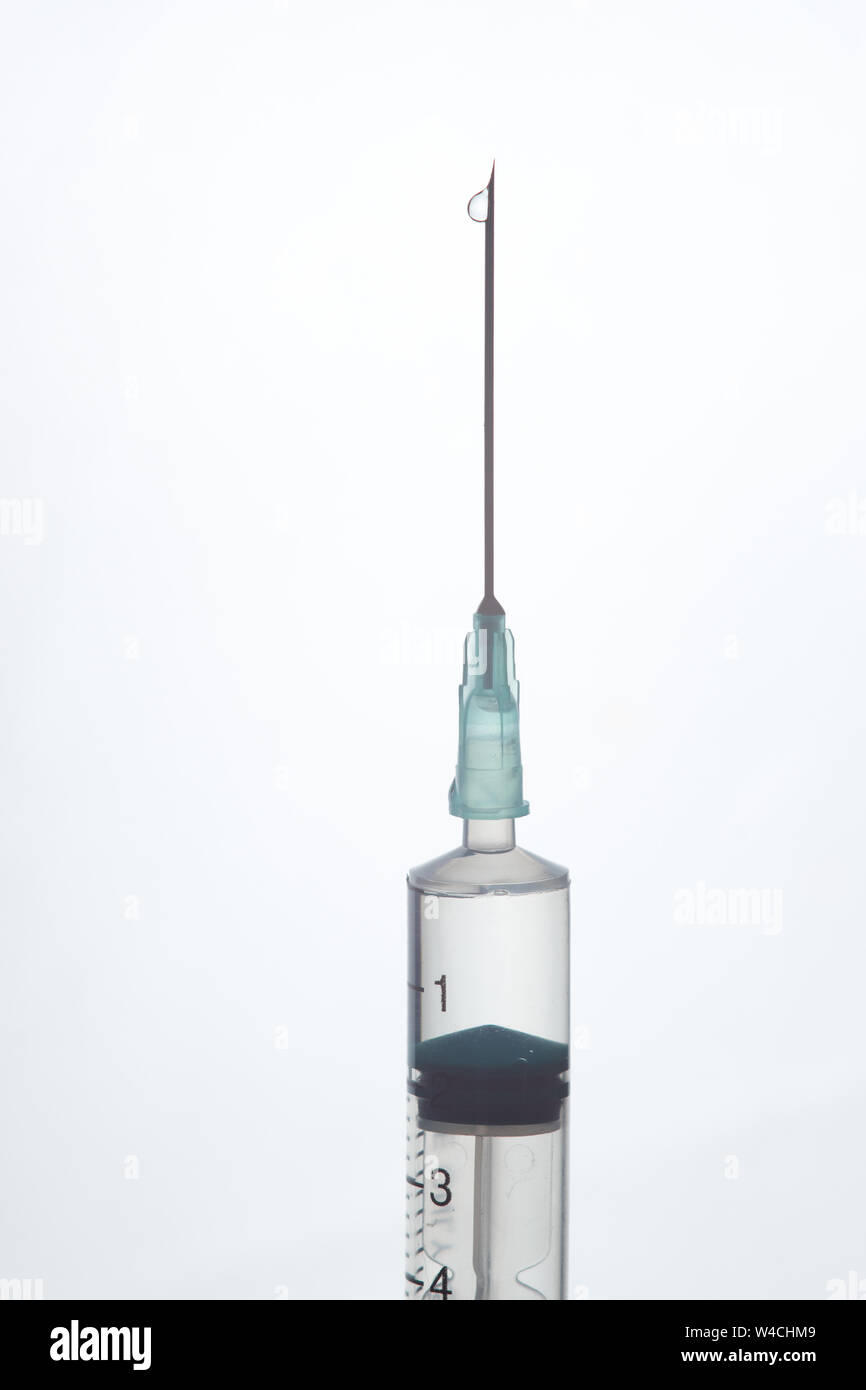 The end of the syringe with a needle filled with liquid on a light ...