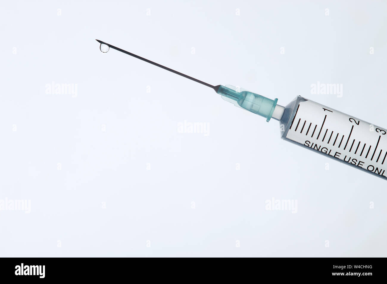 The end of the syringe with a needle filled with liquid on a light ...