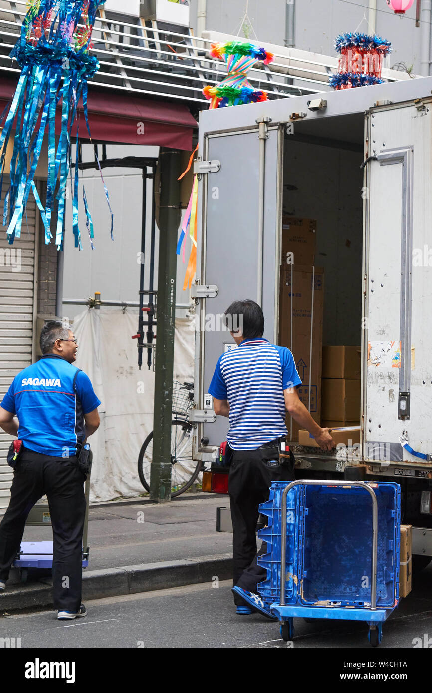 Two Japanese men working for Sagawa talk, unload a delivery truck and ...