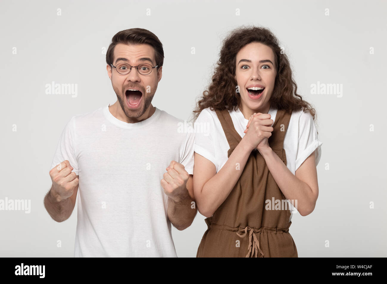 Overjoyed couple feels happy celebrating lucky fortunate moment studio ...