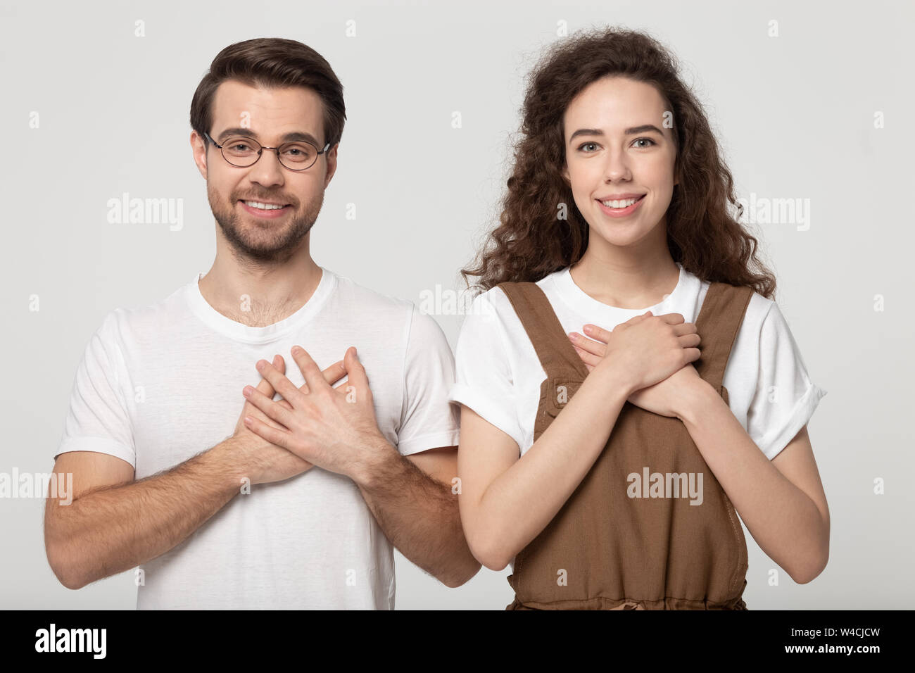 Grateful couple holding hands on chest feeling thankful studio shot ...