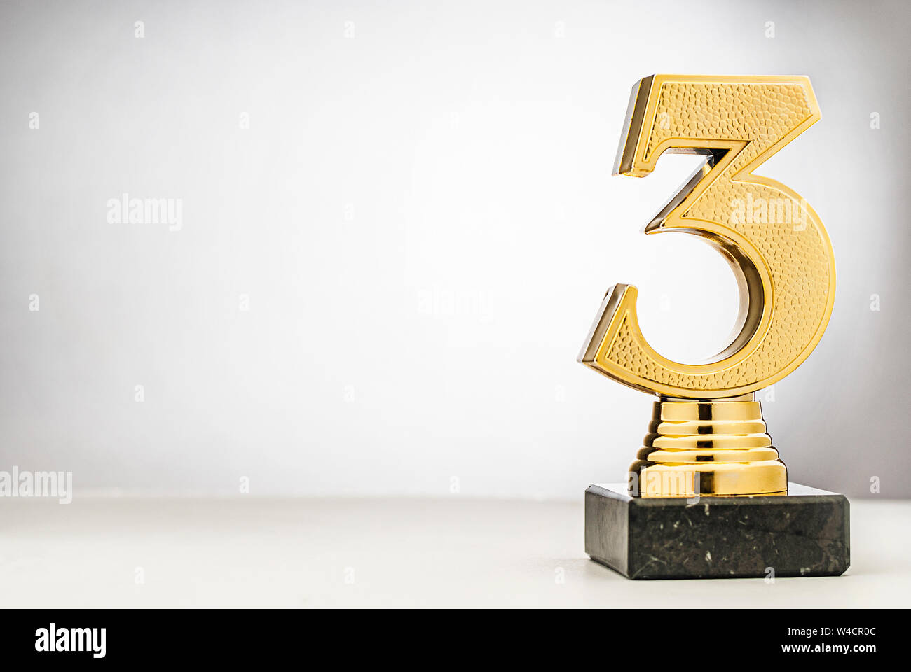 3rd placed runner up metallic gold trophy with a 3D number 3 on a stand ...
