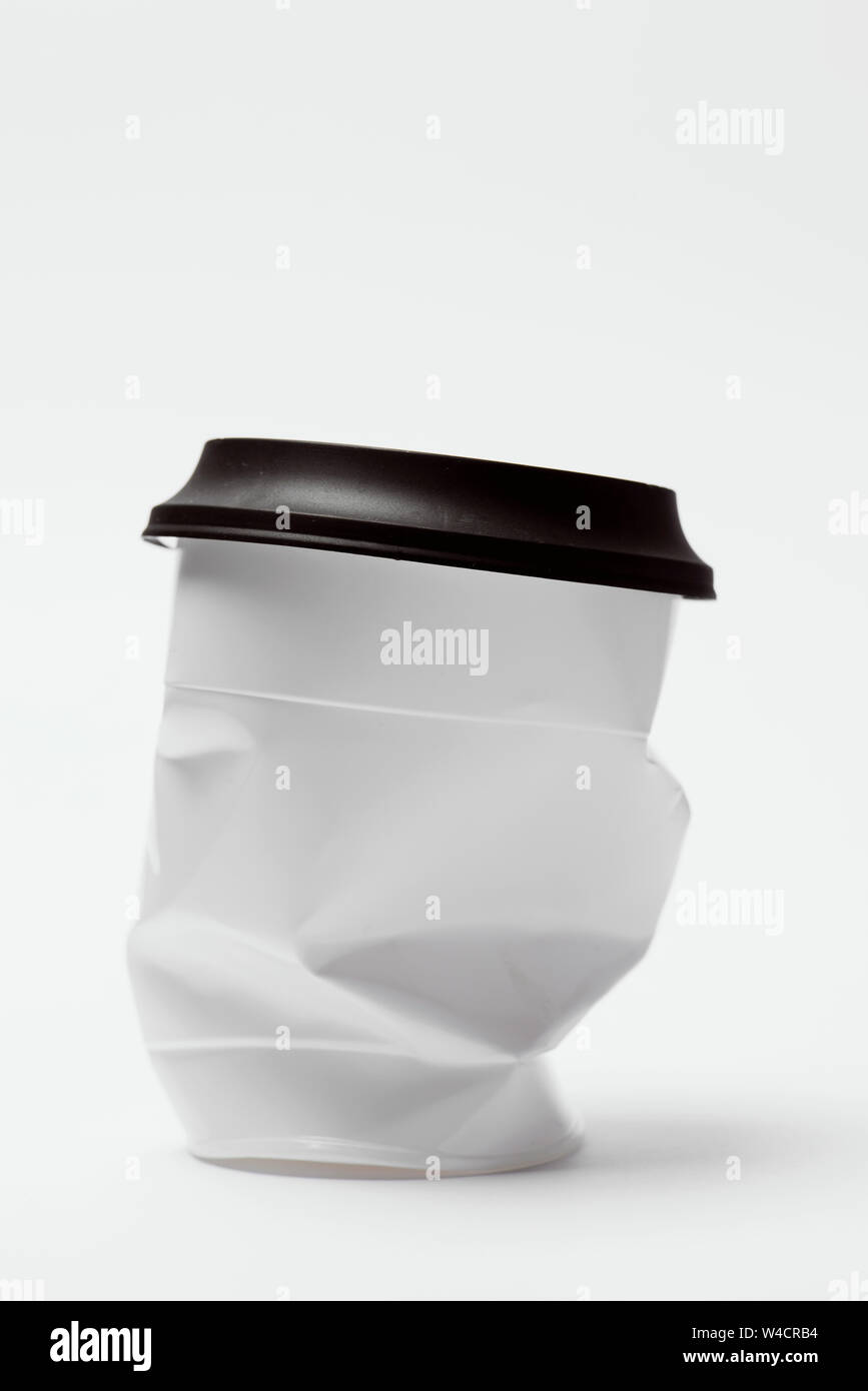 closeup of a smashed white plastic cup, covered with a black lid, on a ...