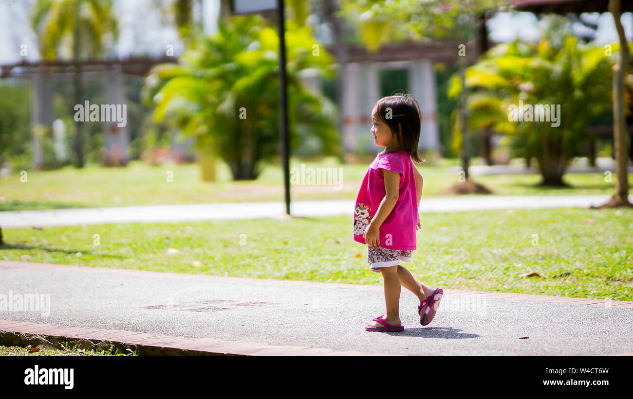 Asian toddler girl running in the park from behind at the spring or ...