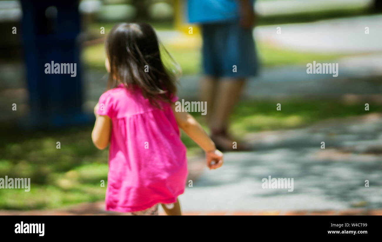 Asian toddler girl running in the park from behind at the spring or ...