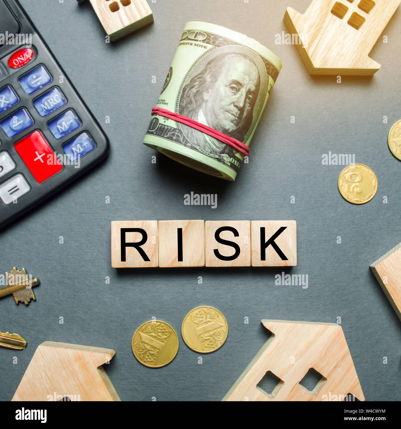Wooden houses, a calculator, keys, coins and blocks with the word Risk ...