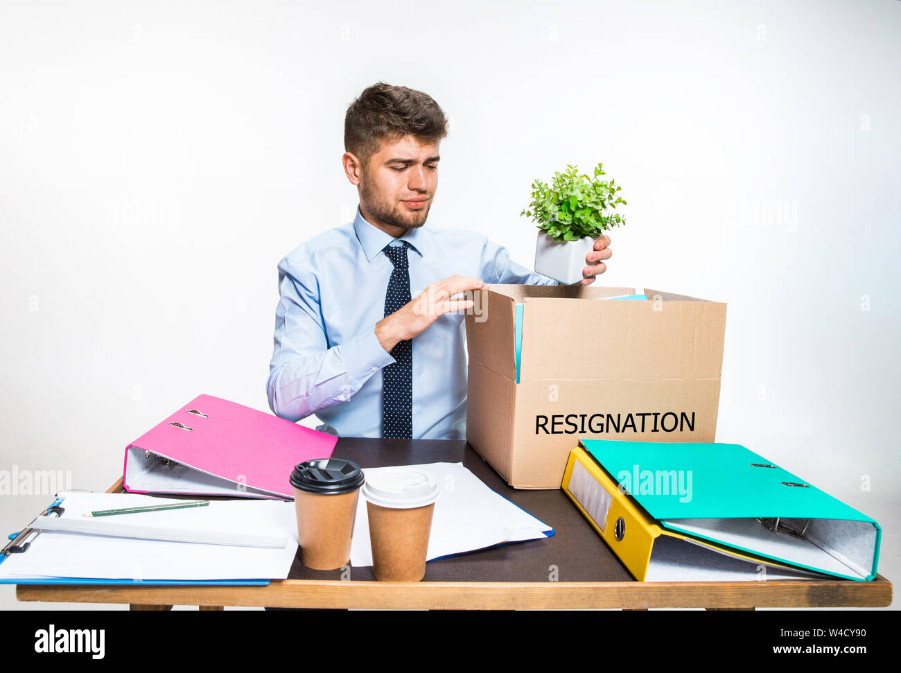 The young man is resigned and folds things in the workplace, folders ...
