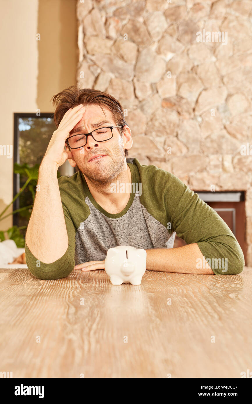 Stressed man in front of a piggy bank worries about a bill Stock Photo ...
