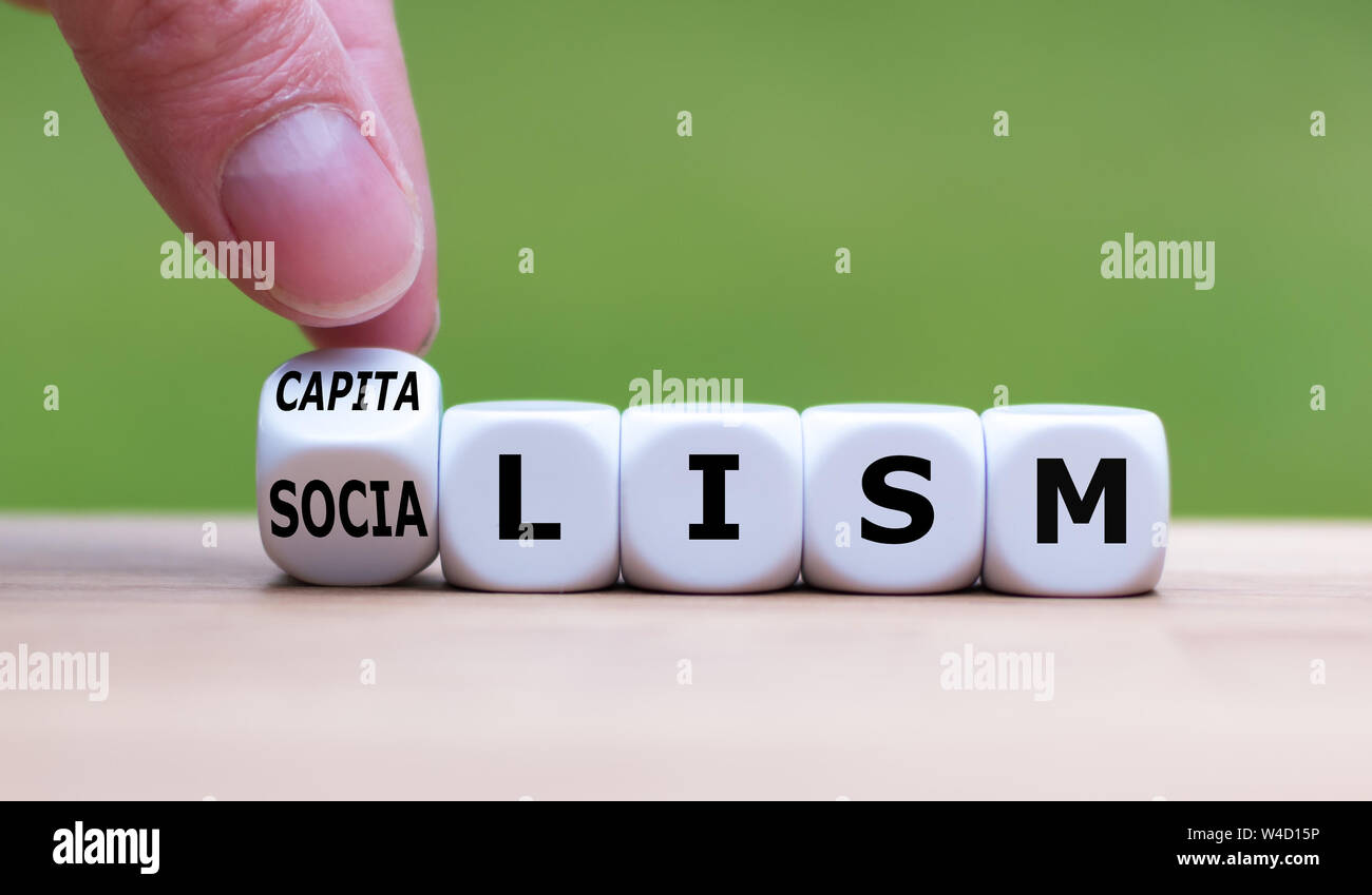 Hand flips a dice and changes the word "Socialism" to "Capitalism", or ...