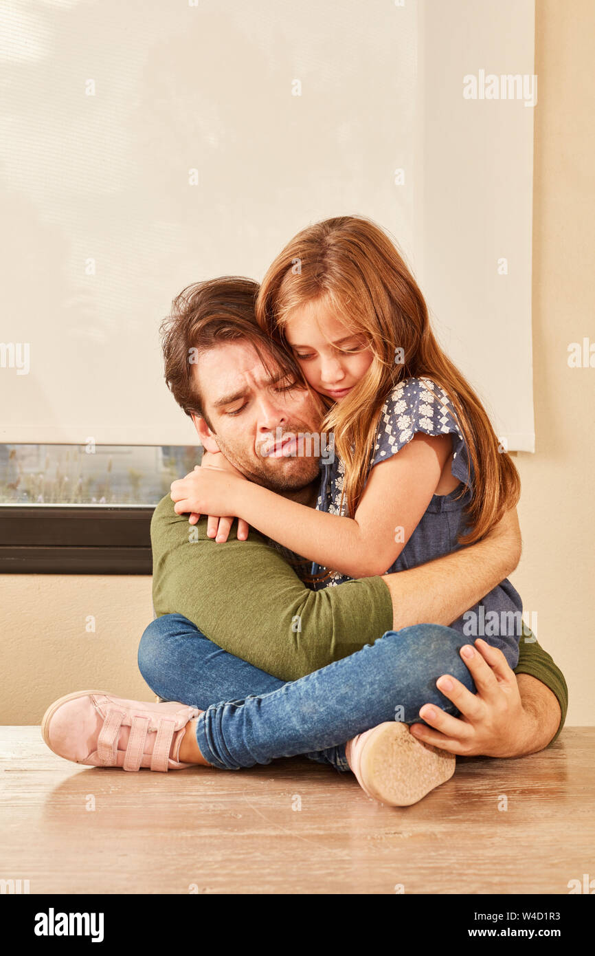 Unhappy father and daughter hold each other in their arms and comfort ...