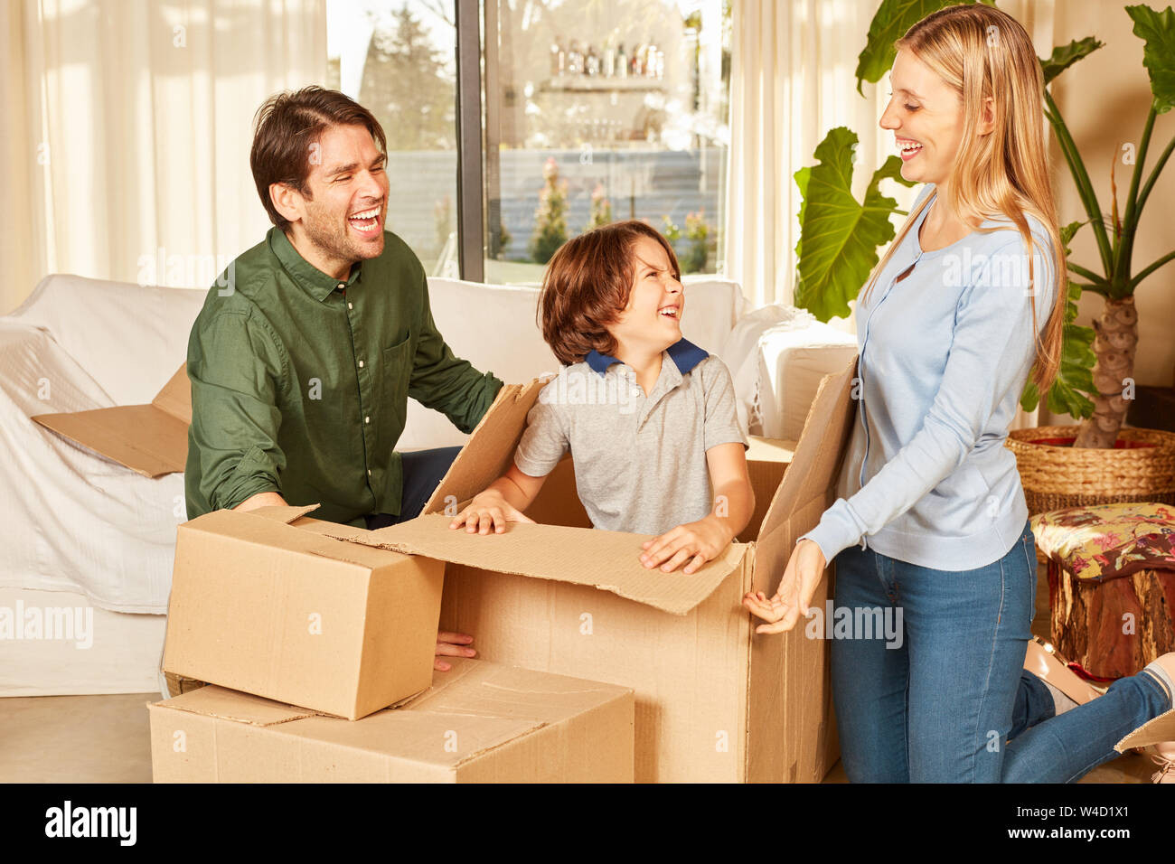 Parents and happy boy in moving carton unpacking in new home Stock ...