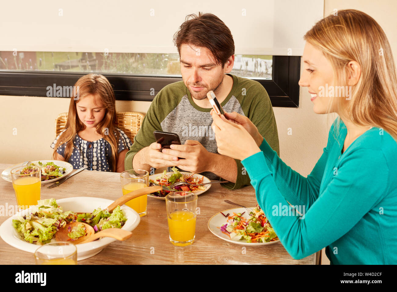 Parents and daughter using smartphone and cellphone together at the ...