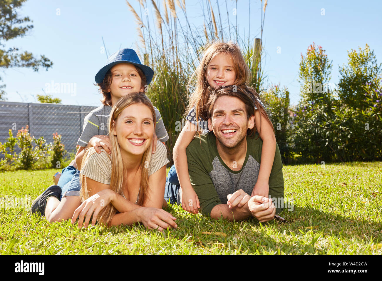 Happy family and two kids is lying on a meadow in the garden in summer ...