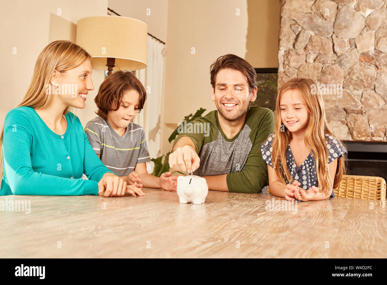 Happy family with two kids puts money in a piggy bank for the future ...