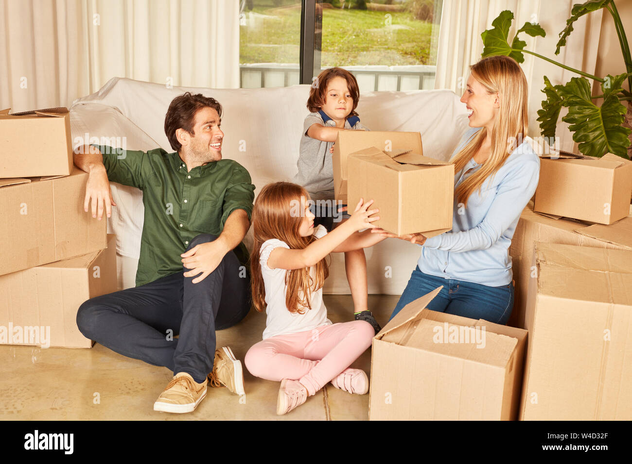 Family with two children is sitting in the new apartment moving between ...