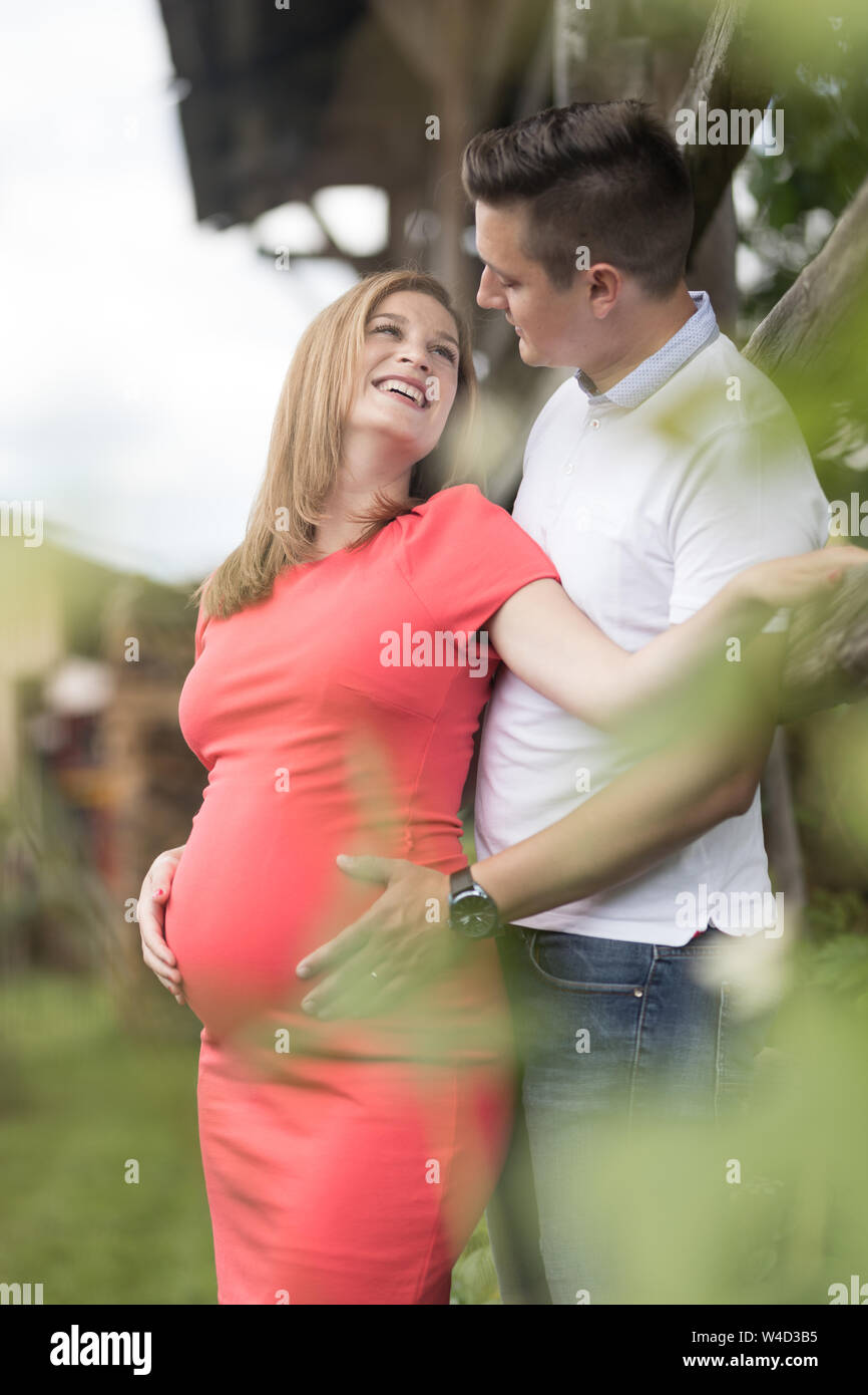 Young happy pregnant couple hugging at countryside by hayrack Stock ...