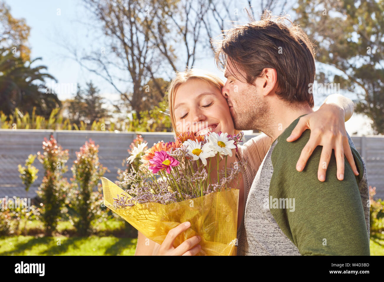 Man kisses his girlfriend and gives her a bouquet of flowers to welcome ...