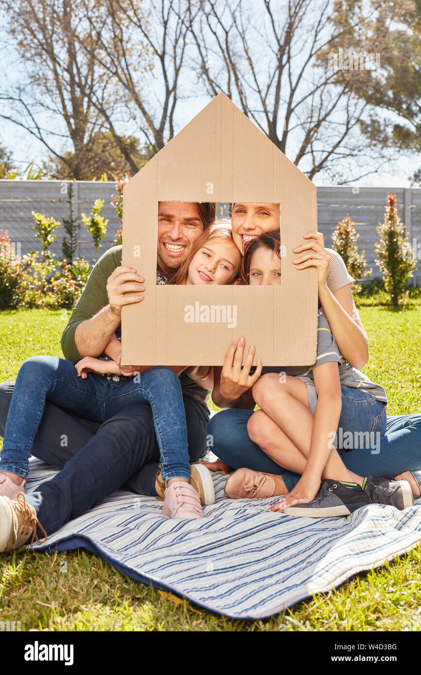 Parents and two kids are holding a model house as a symbol of home and ...