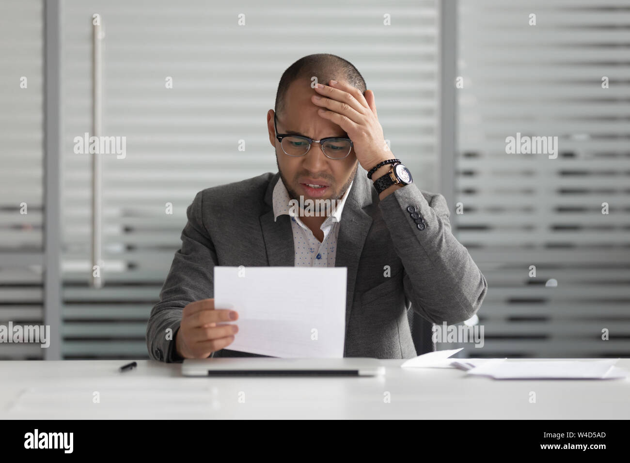 Frustrated upset african businessman reading bad news in mail letter ...