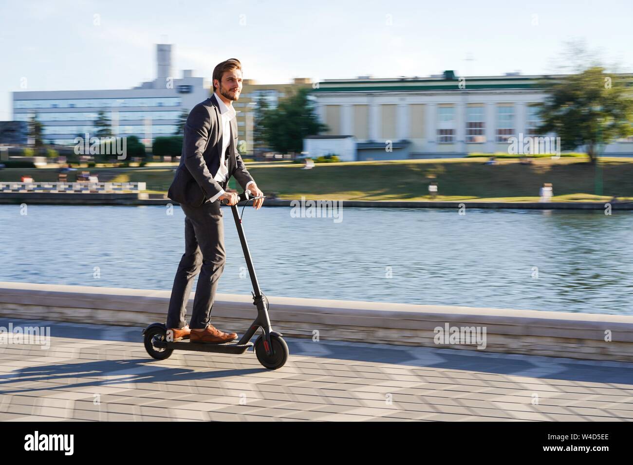 Young business man in a suit riding an electric scooter on a business ...