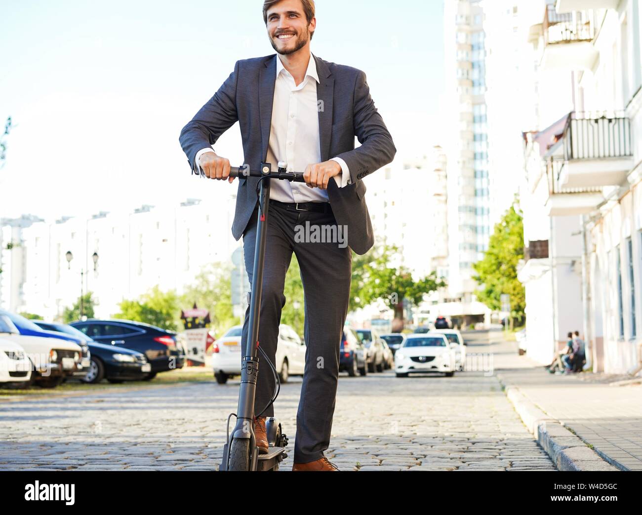 Young business man in a suit riding an electric scooter on a business ...