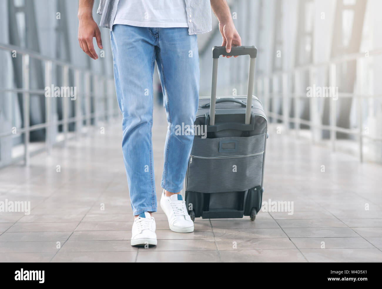 Man walking with luggage at airport corridor Stock Photo - Alamy
