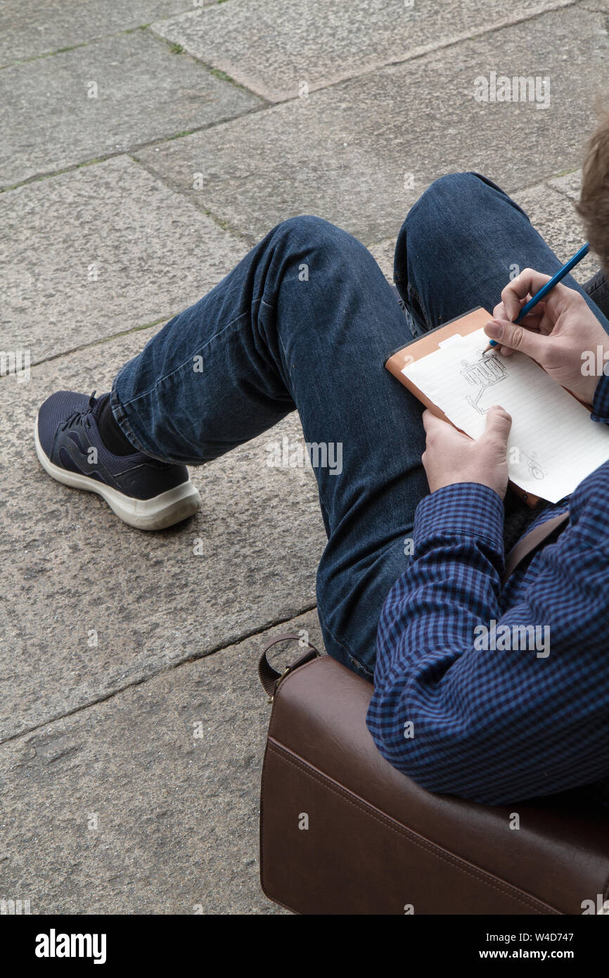 Man sitting on floor drawing on paper notebook. Artist on outdoor Stock ...