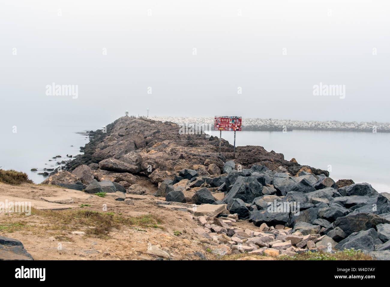 Rock jetty has a very treacherous surface and a warning sign to ...