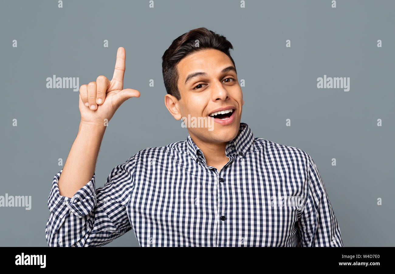 Handsome guy pointing finger upwards on gray background Stock Photo - Alamy