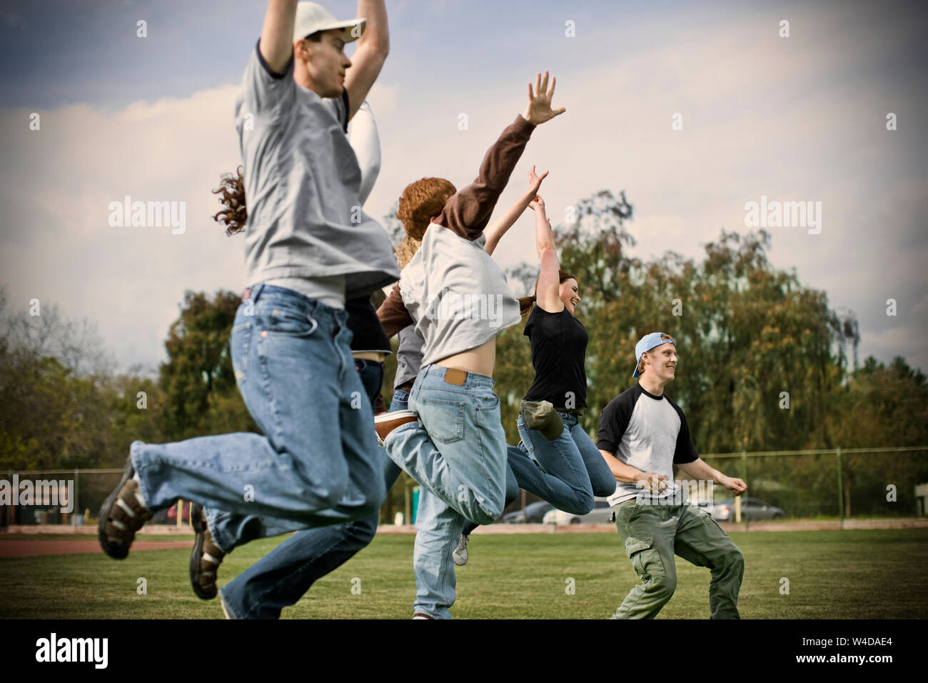Young adults jumping in the air with their arms raised on a sports ...