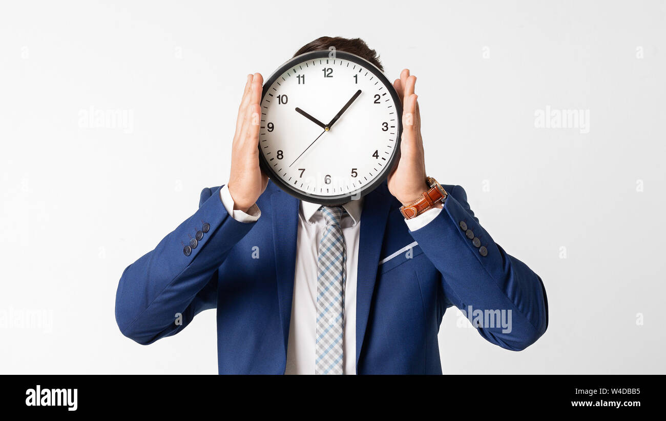 Man hiding his face behind clock on white background Stock Photo - Alamy