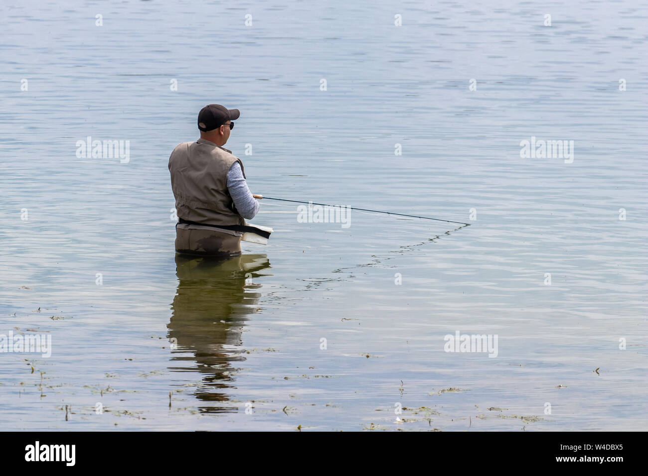 Fisherman in wadders fishing in the water at Pitsford Reservoir ...