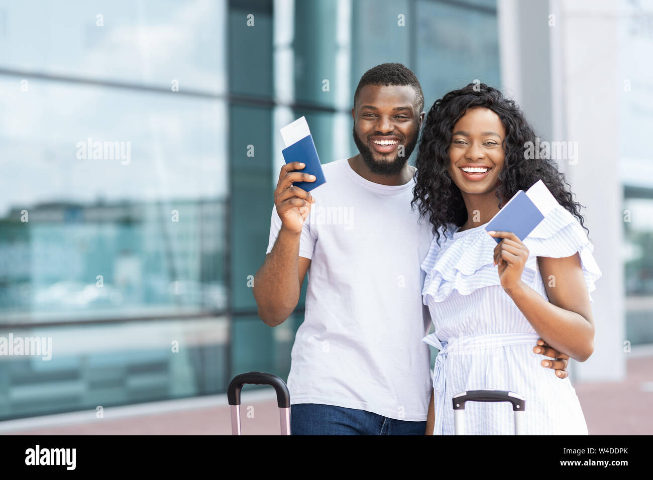 African couple smiling with flight tickets and passports at airport ...