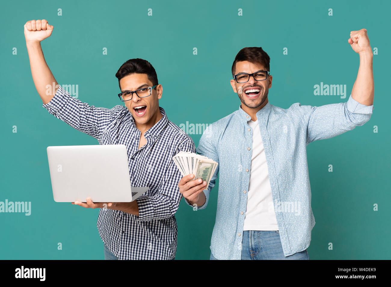 Two Excited Guys Holding Laptop And Money Celebrating Success Stock ...