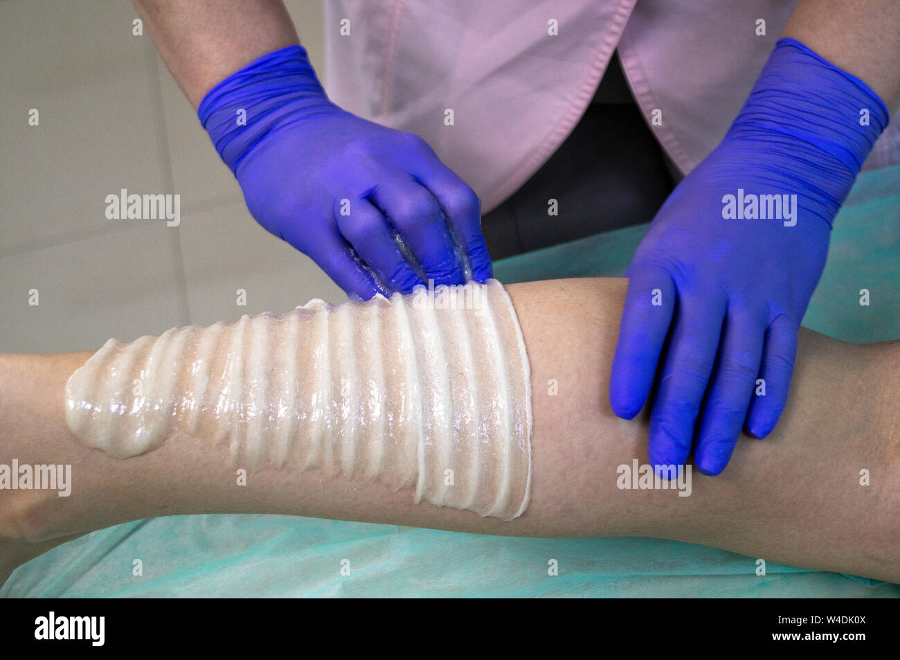 The master in the salon makes the girl sugaring her legs. Natural ...