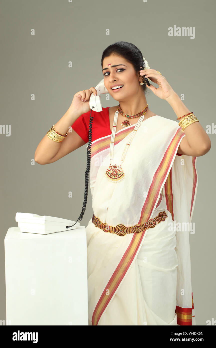 South Indian woman talking on landline phone and mobile phone Stock ...