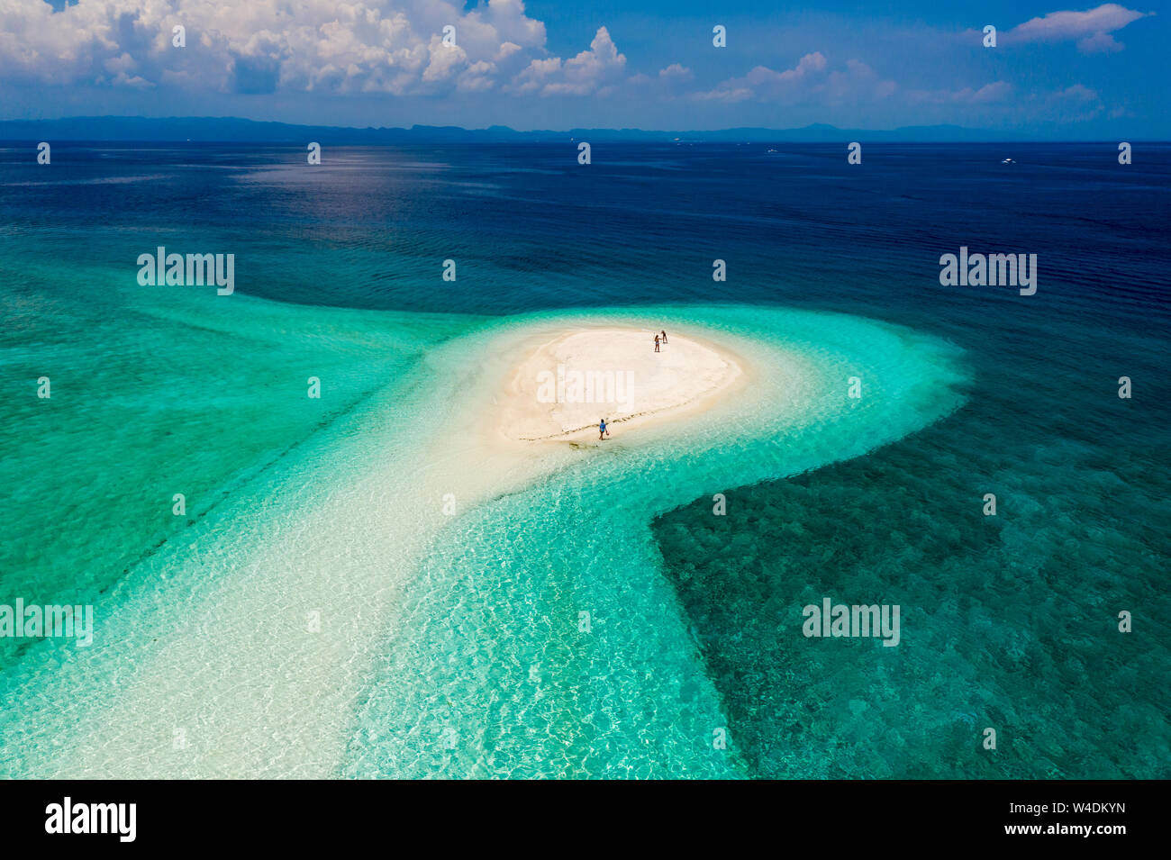 Aerial view of a tiny sandy beach surrounded by coral reef on a ...
