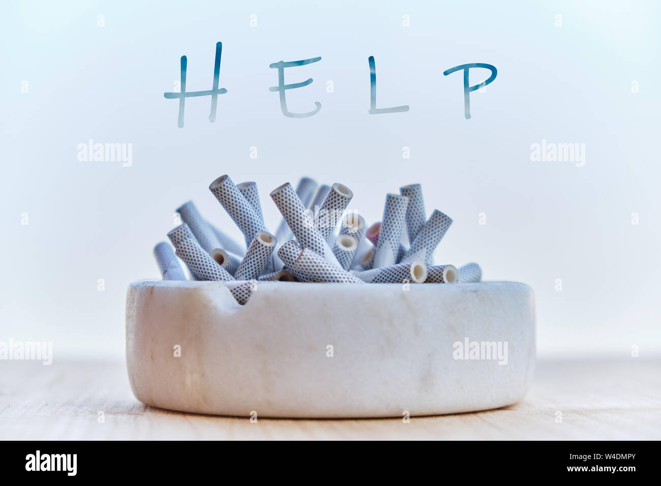 Marble ashtray full of cigarettes and the word HELP written above ...