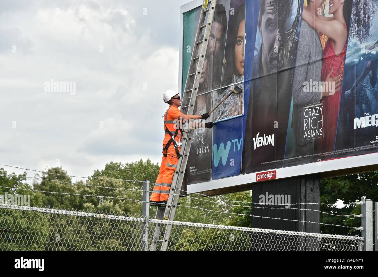 Man on ladder installing advertising poster Stock Photo - Alamy