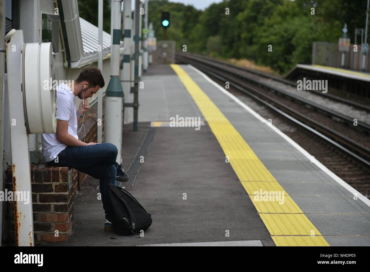 Man on train station platform using his device Stock Photo - Alamy