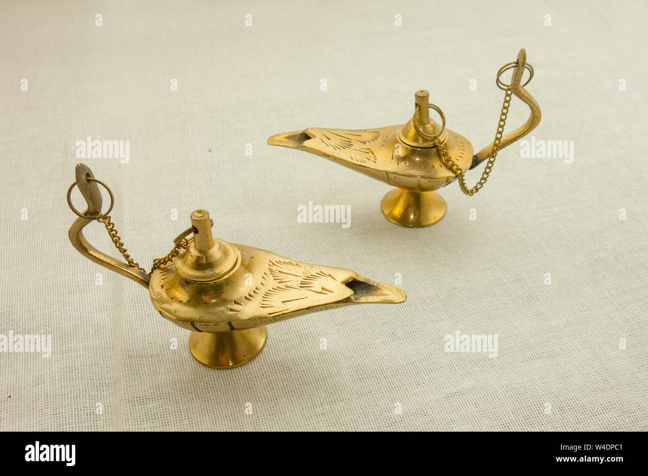 Two ancient gold Arabian lamps on woven fabric background. Closeup ...