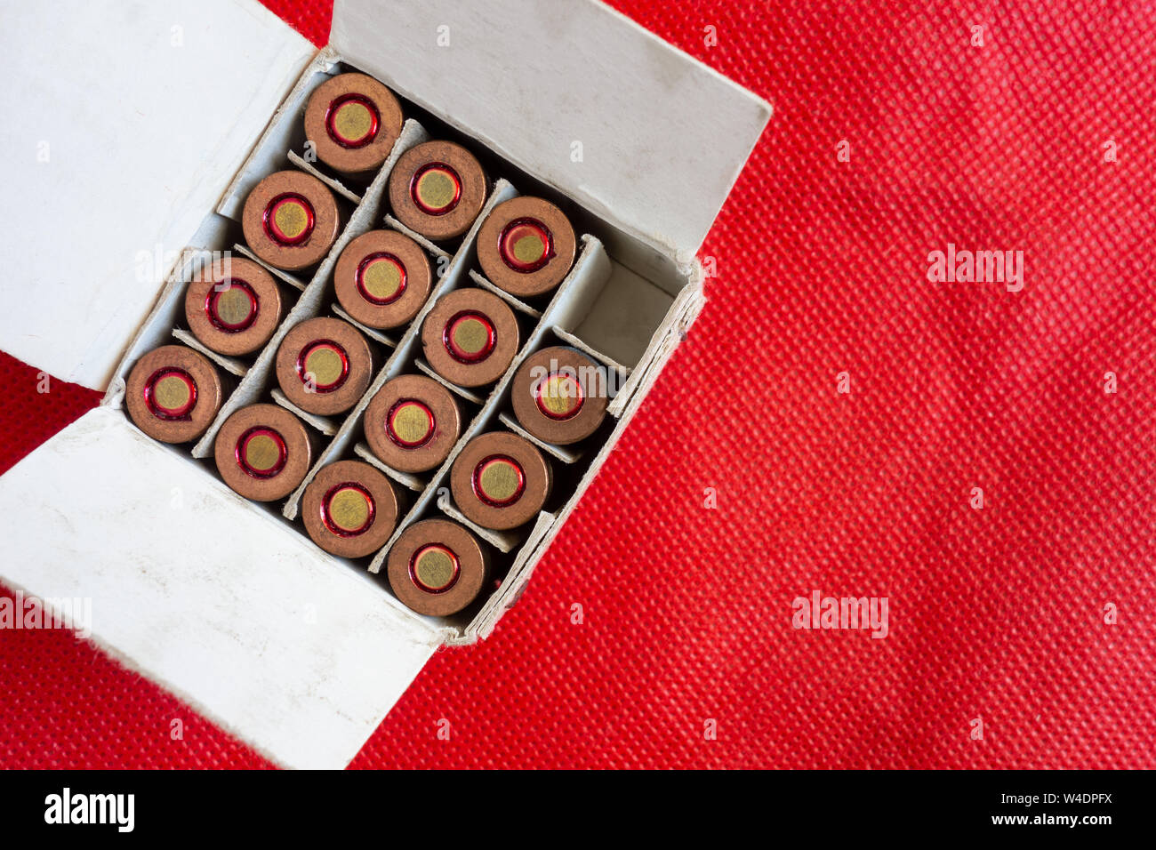 Open box of gun cartridges on red background. One cell is empty as a ...