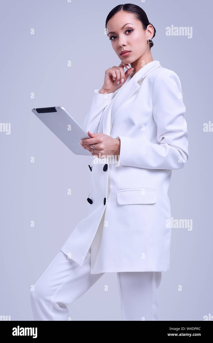 Portrait of a cute and gorgeous latin women in fashion white suit with ...