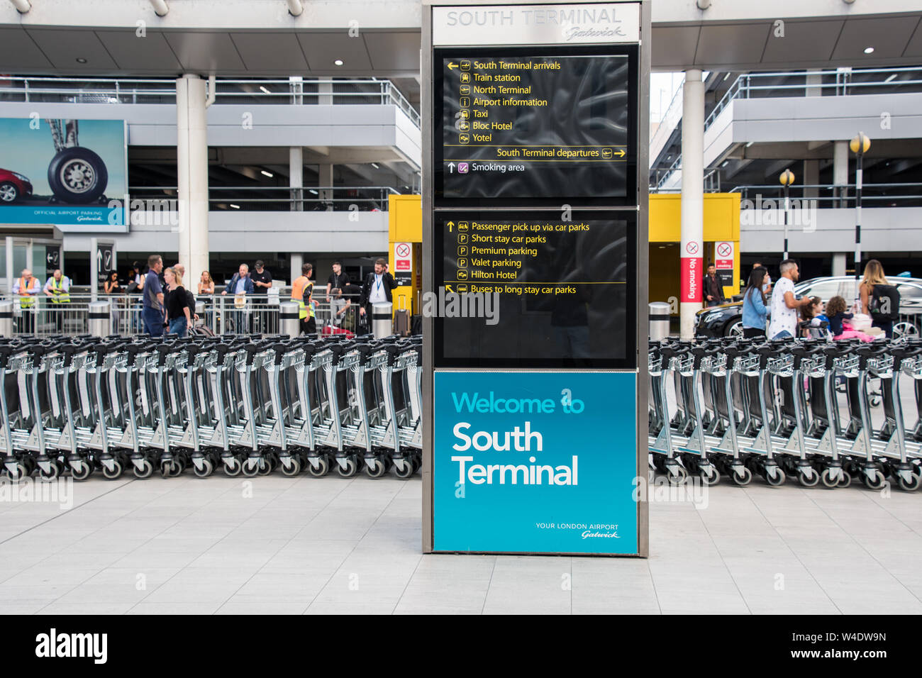 Gatwick South Terminal sign board with trollies and people in ...