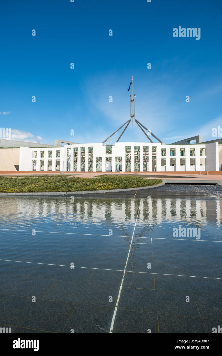 Gleaming white Parliament House of Australia is reflected in shallow ...