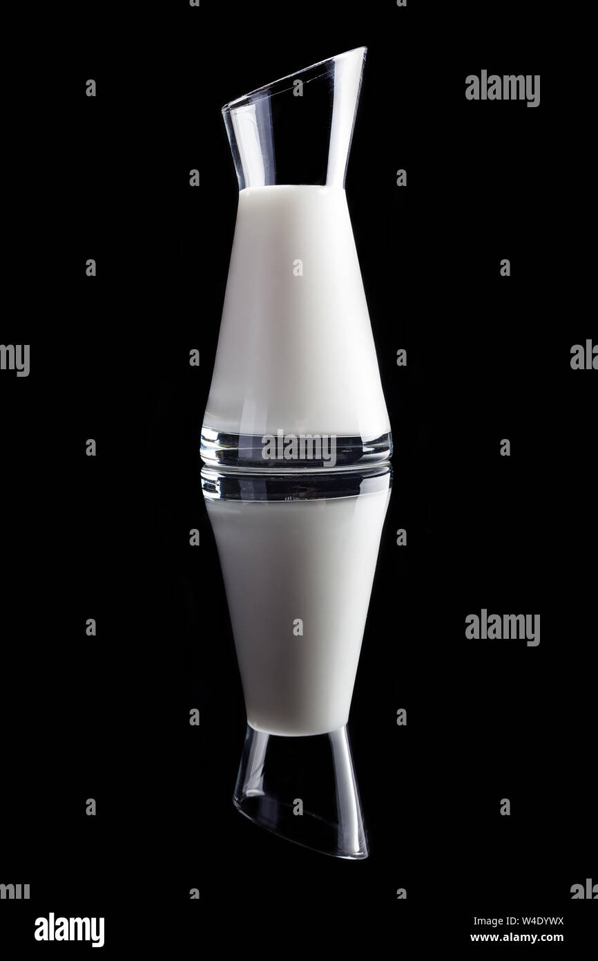 Glass pitcher with white yogurt on black background from side vertical ...