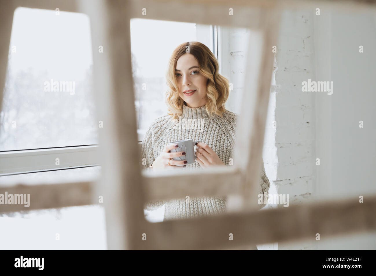 Beautiful blonde girl drinking tea by the window Stock Photo - Alamy