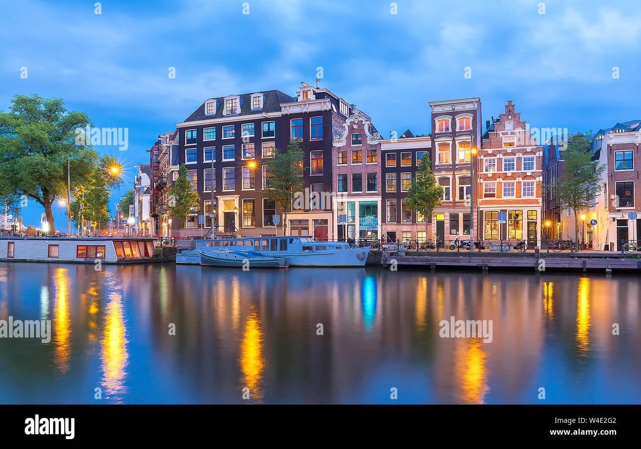 Night city view of Amsterdam canal, typical dutch houses and boats ...